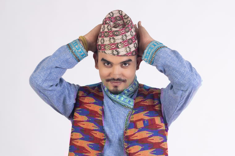 A excited young boy wearing traditional Nepali clothes adjusts his ...