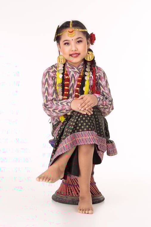 A glad little girl sitting on a muda with her knees crossed and her ...