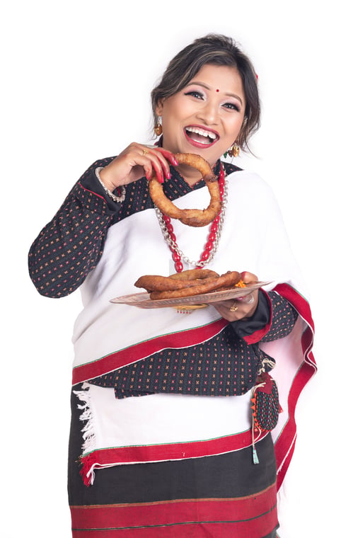 A very delighted woman wearing traditional Newari attire eating Selroti ...