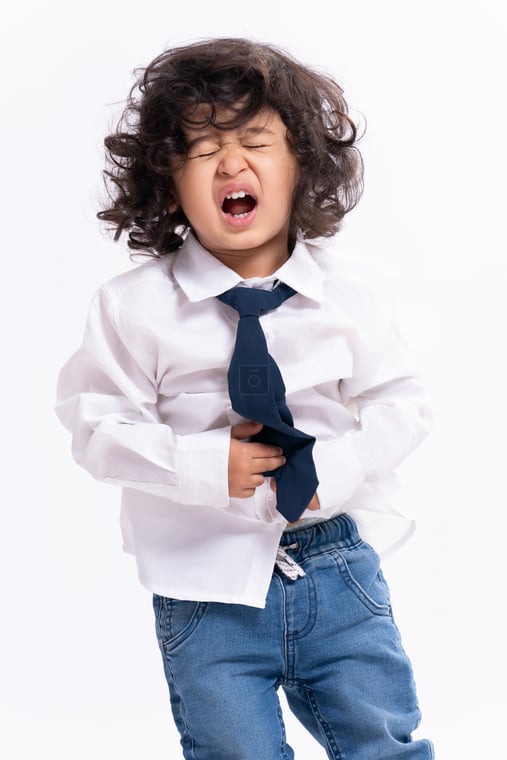 Little child in a casual outfit weeping due to the stomach pain ...